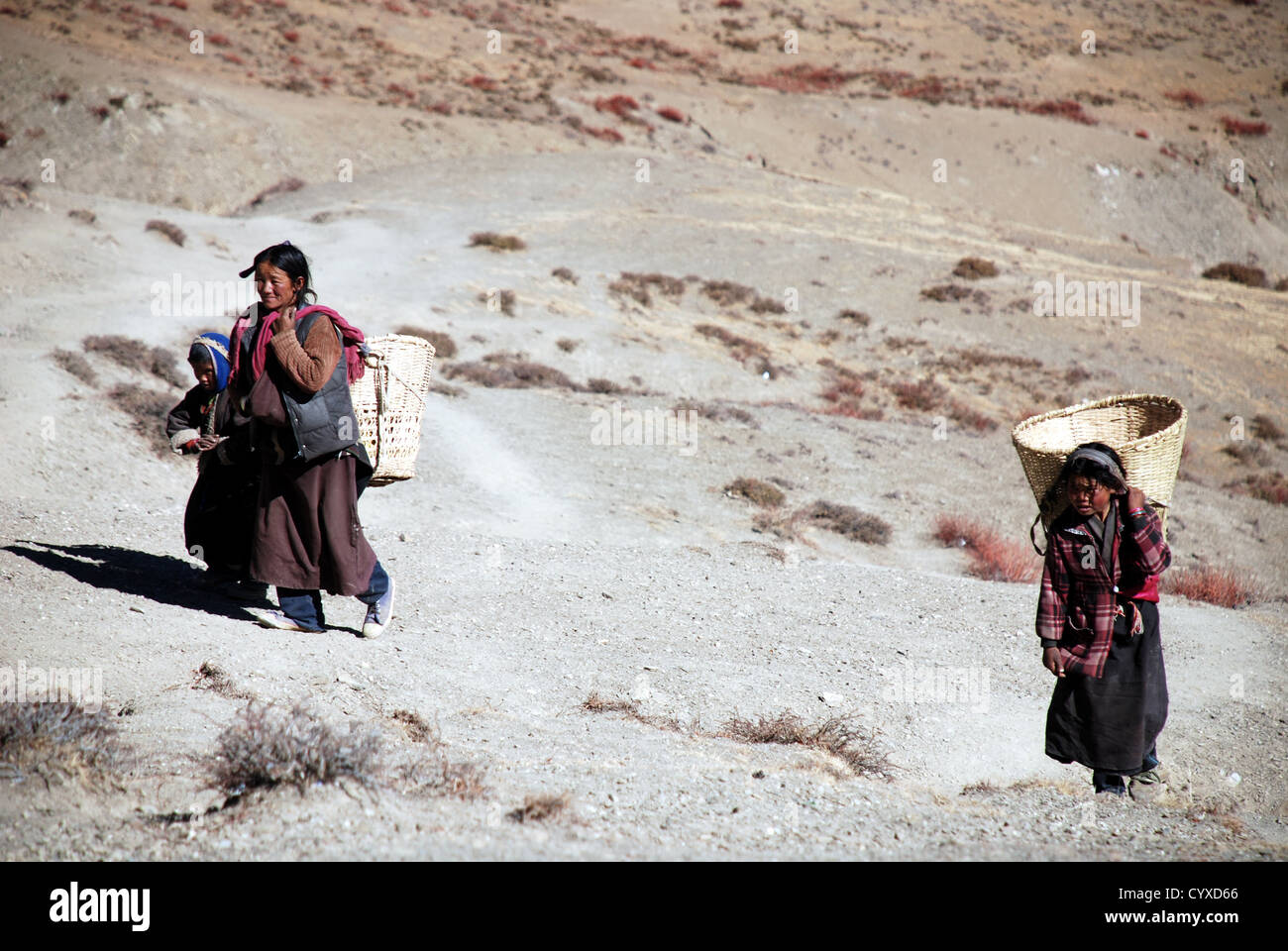 a mother and children carrying baskets and dressed in Tibetan clothing ...