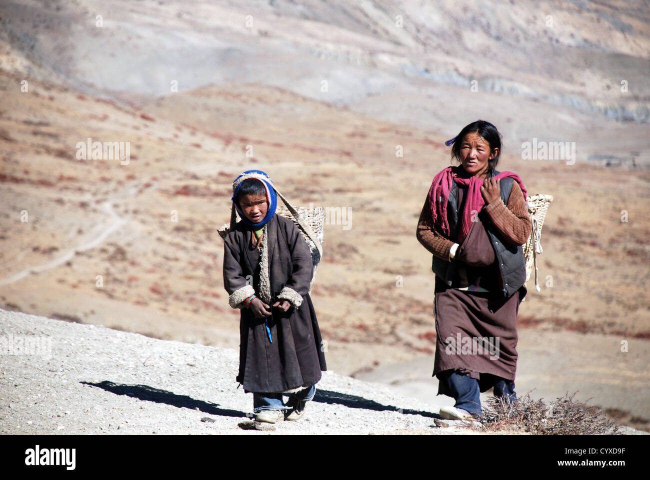 a mother and child carrying baskets and dressed in Tibetan clothing ...