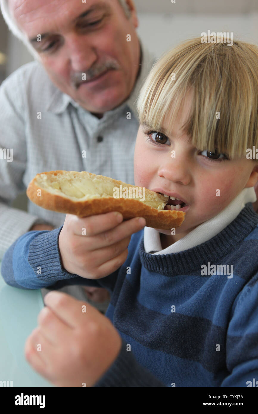 Boy eating bread with his grandfather Stock Photo - Alamy