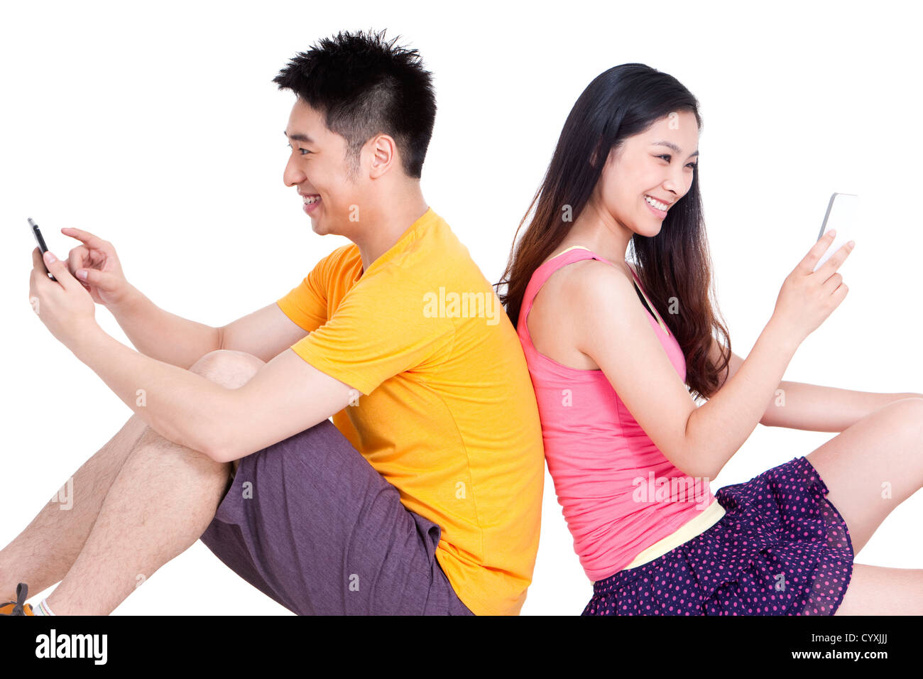 Happy young couple sitting back to back with smart phones Stock Photo ...