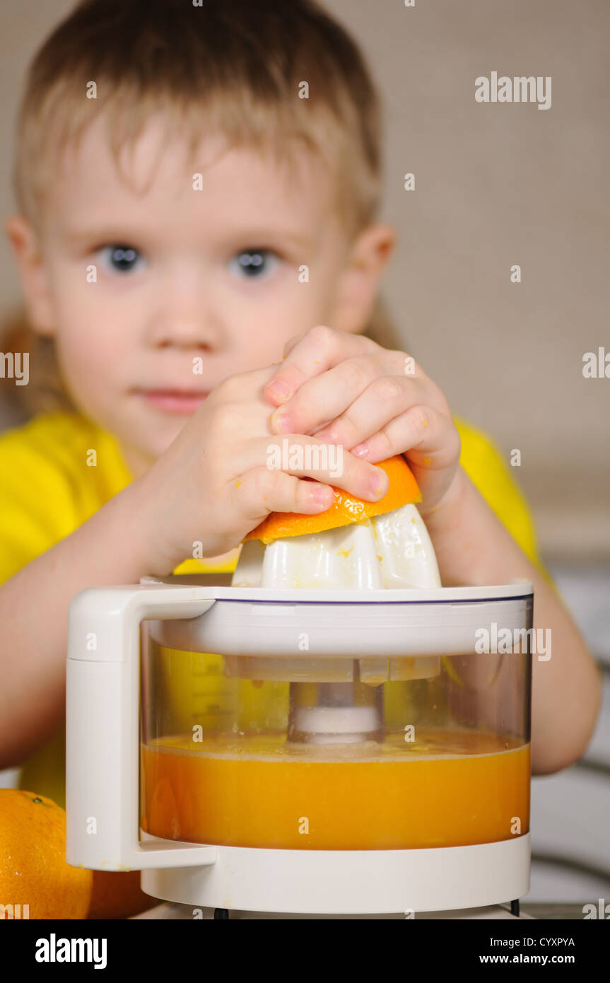 The child in a yellow vest to wring out juice from an orange Stock ...