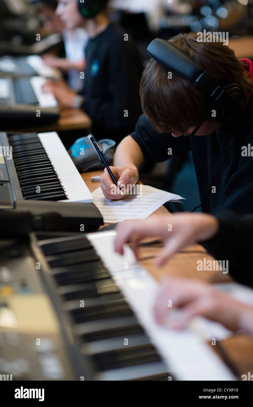 Pupils playing pianoand composing in a music class lesson at a ...
