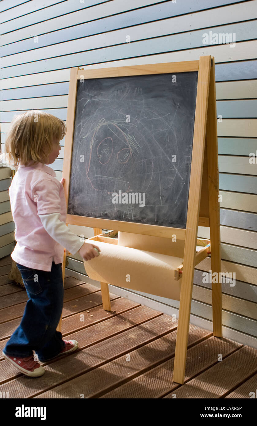 Cute young caucasian boy writing on a blackboard in school or ...