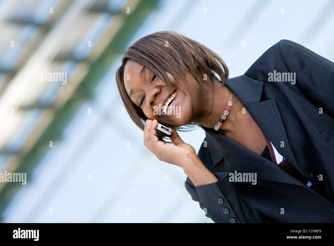 African american business woman talking on a mobile cell phone in front of an office building ...
