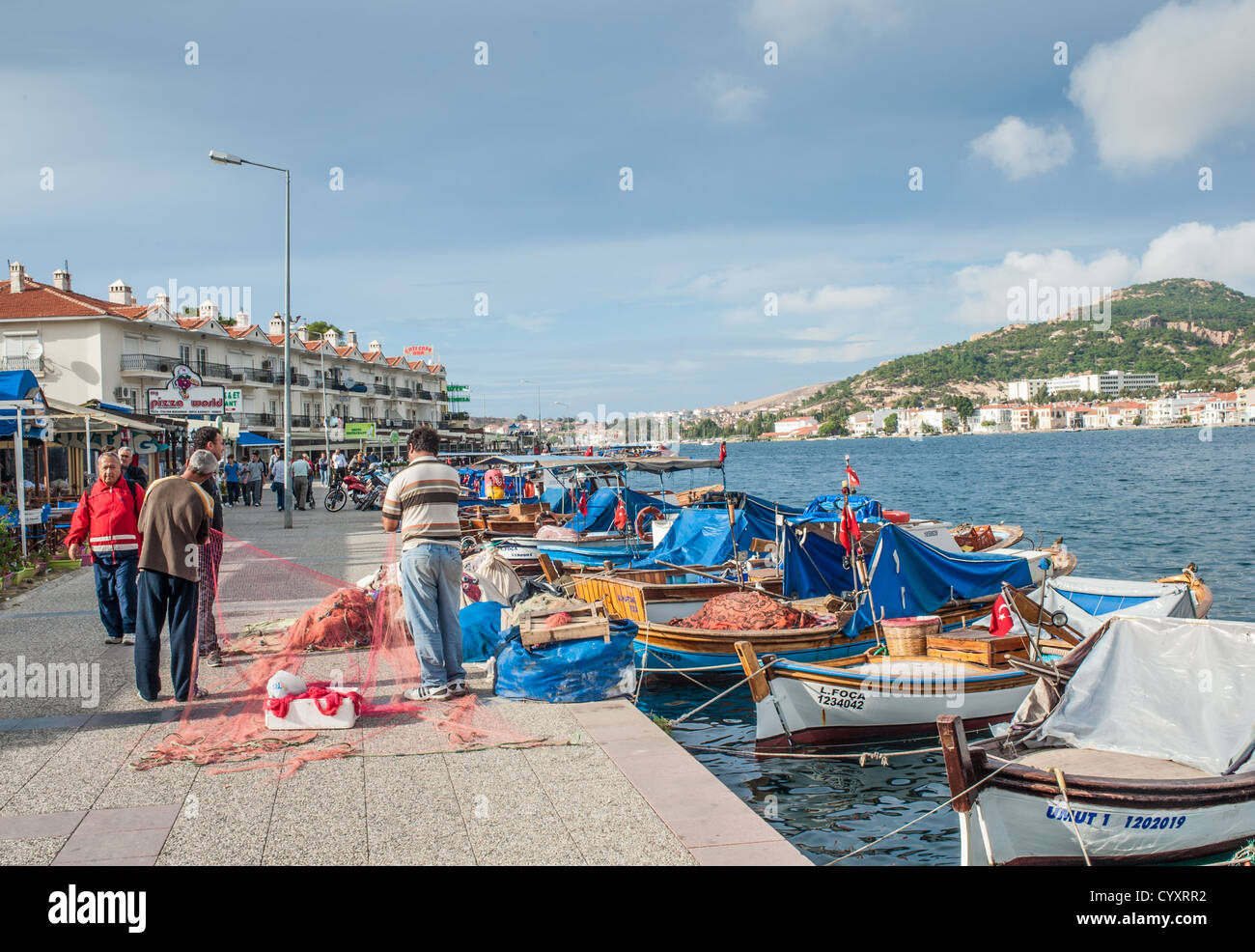 Fishermen examining fishing nets on the quayside in Foca, Turkey ...