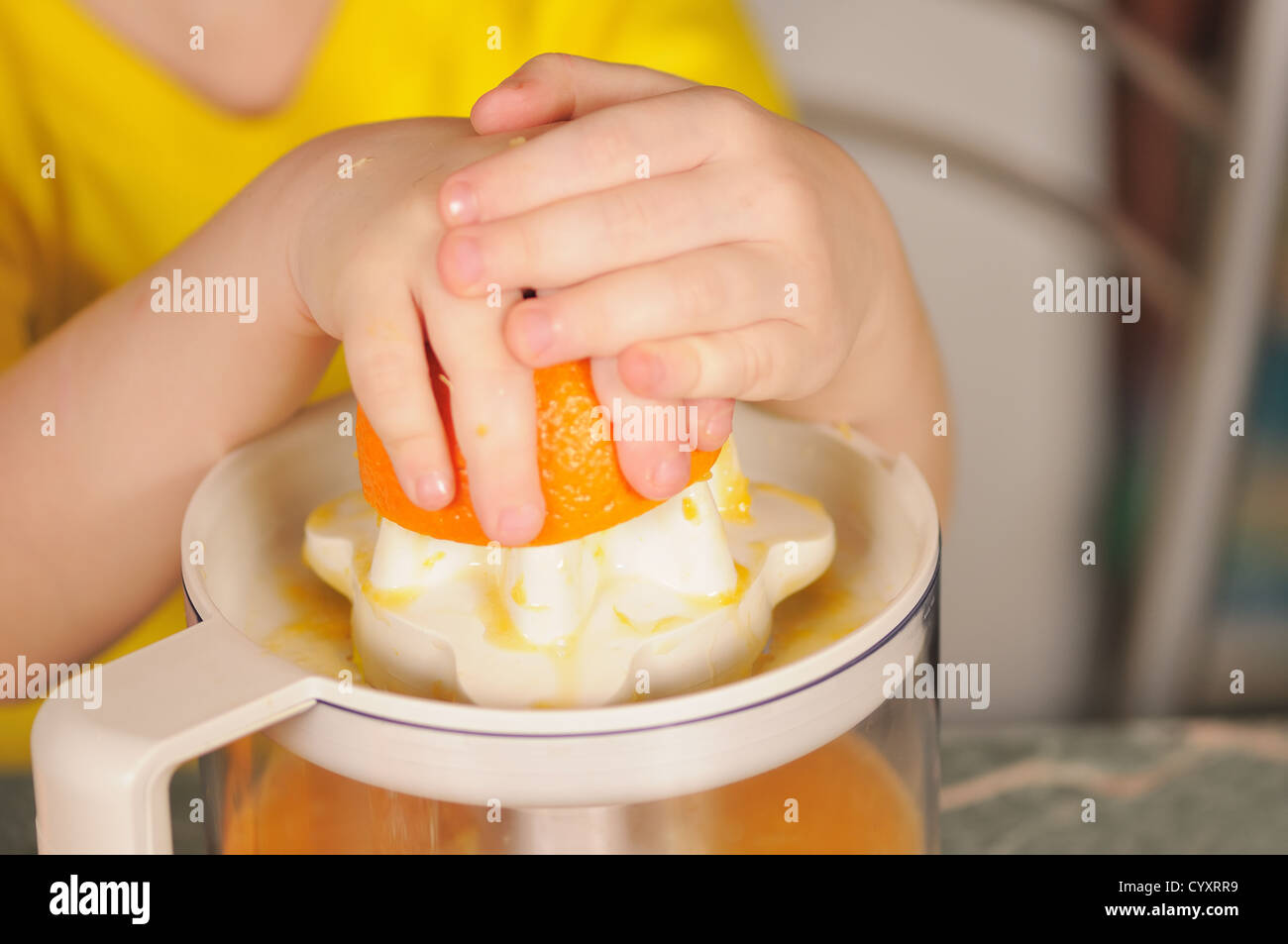 The child in a yellow vest to wring out juice from an orange Stock ...