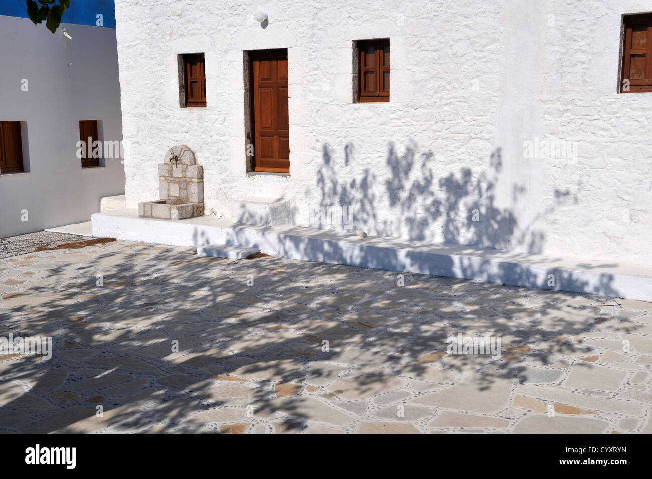 Shadow of tree on patio and white wall of Greek building. Monastery of ...