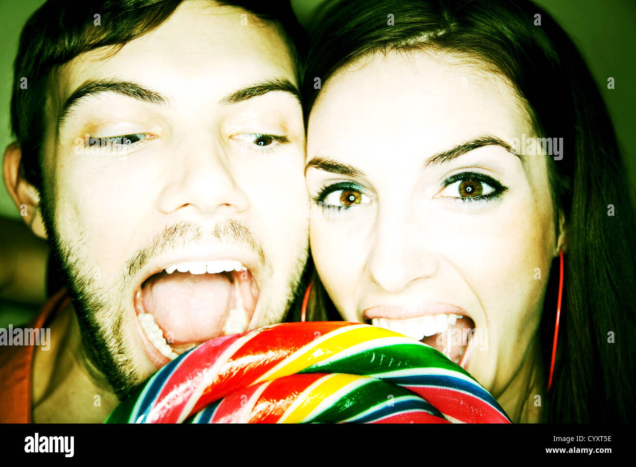 Cute Couple Biting into Big Colorful Lollipop Stock Photo - Alamy