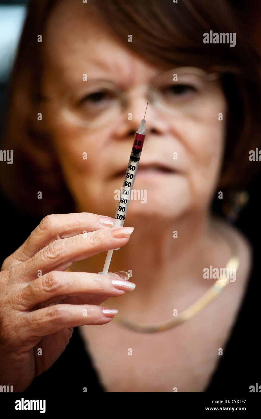 Senior woman looking at small hypodermic needle Stock Photo - Alamy