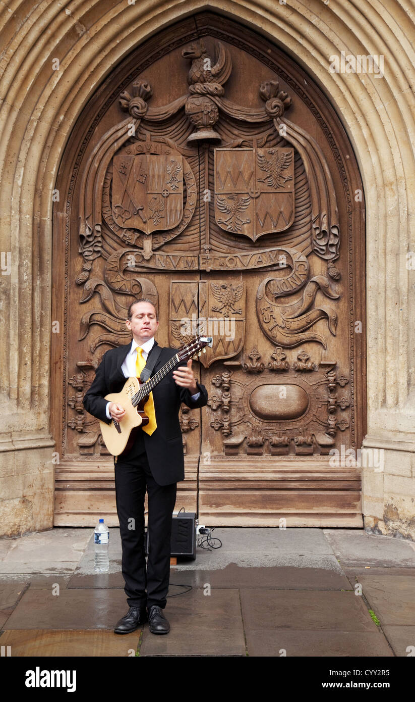 A street musician busker playing guitar at the Abbey door, Bath ...