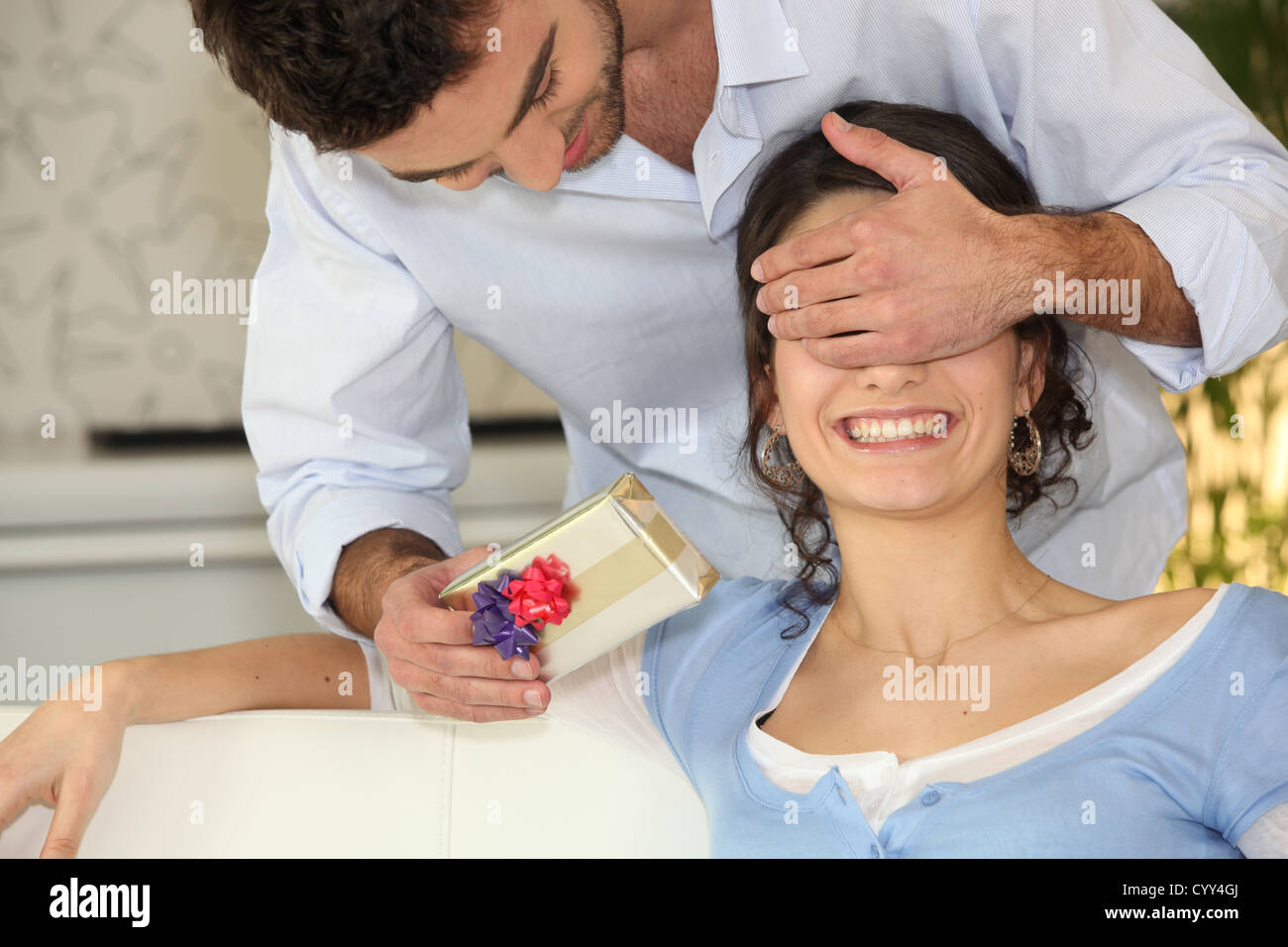Man surprising woman with gift Stock Photo - Alamy