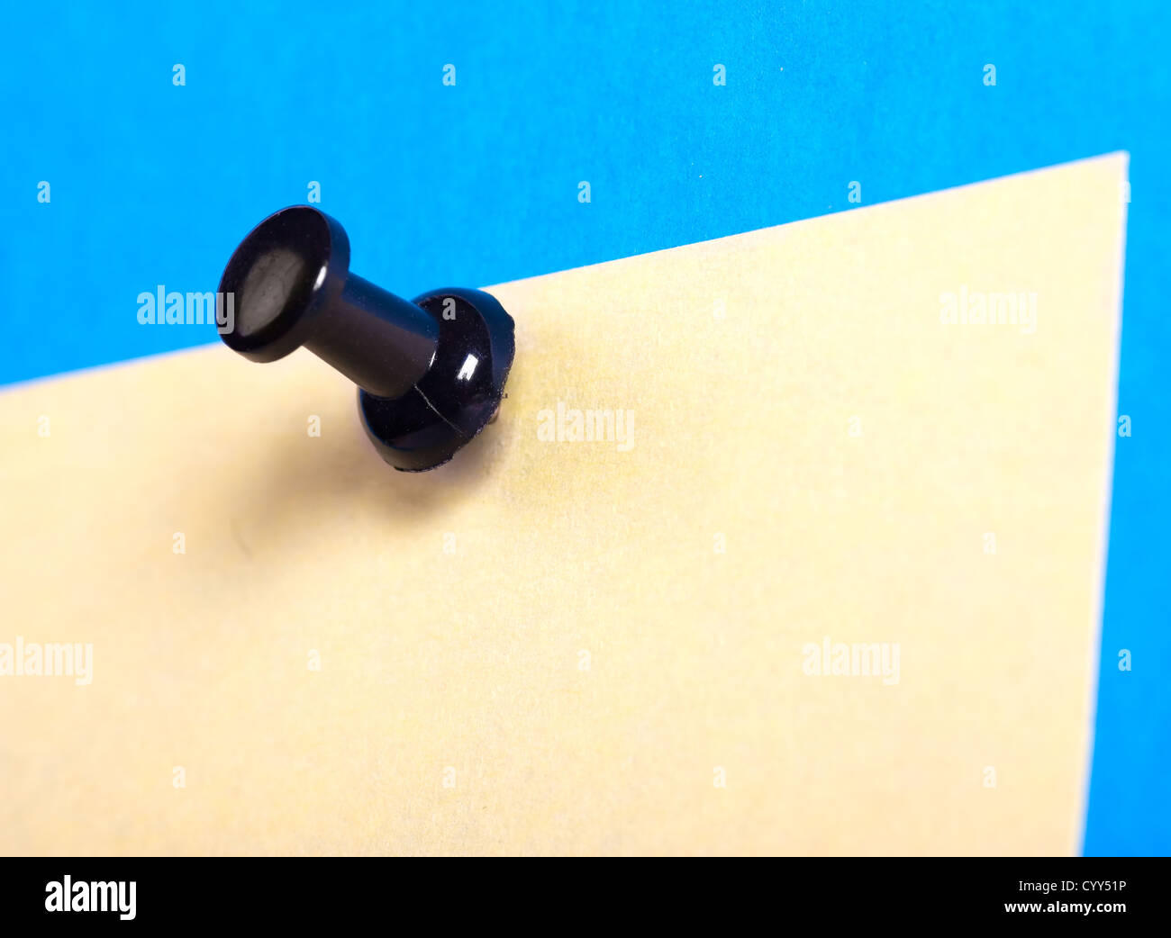 Yellow note on a blue background attached by black thumbtack Stock ...