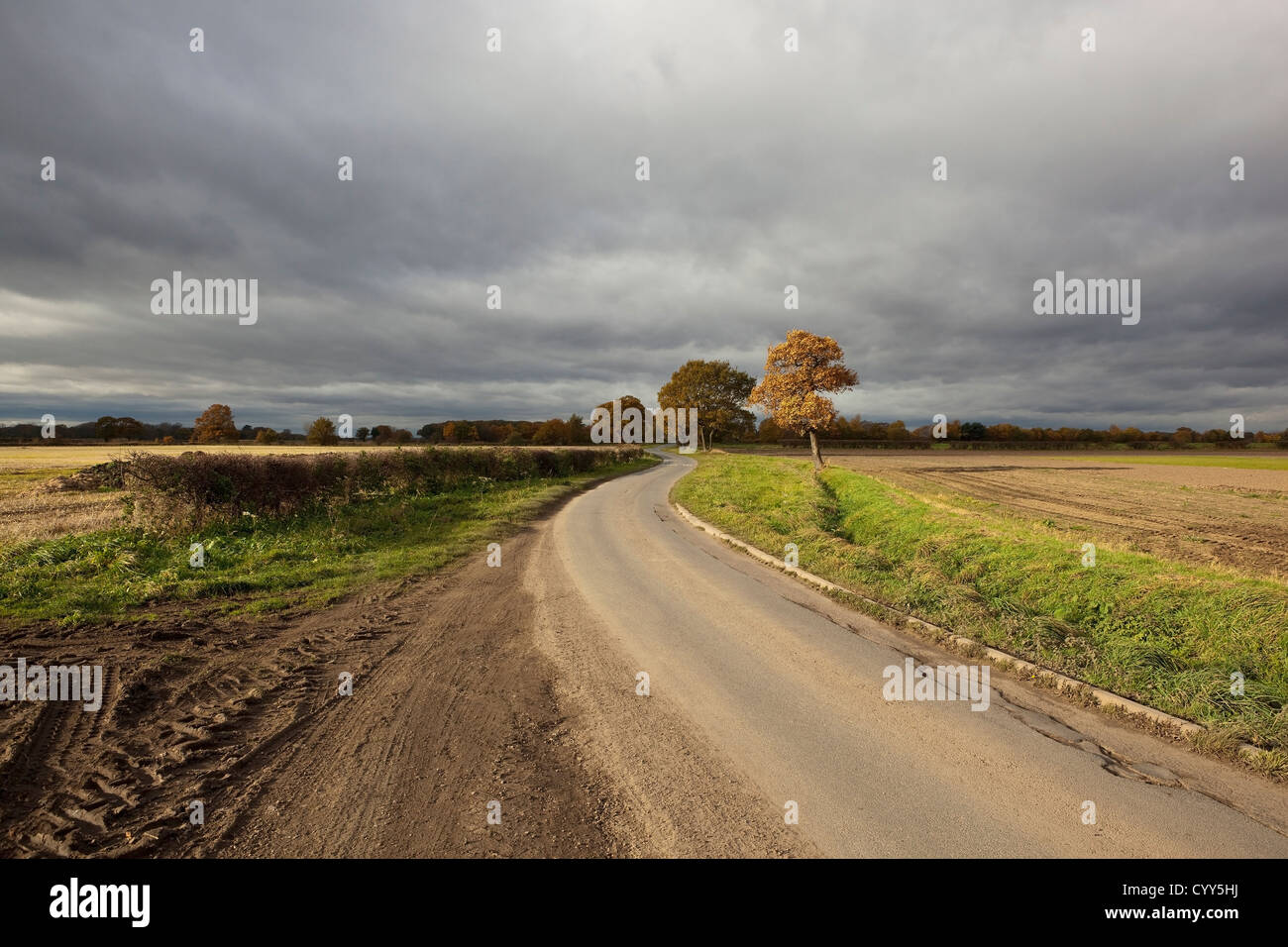 A stormy autumn landscape with a winding rural road through farmland ...