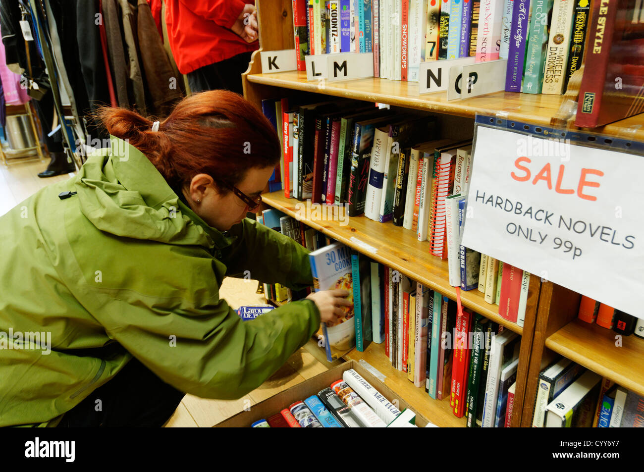 A young woman browsing books in a charity shop in England Stock Photo ...