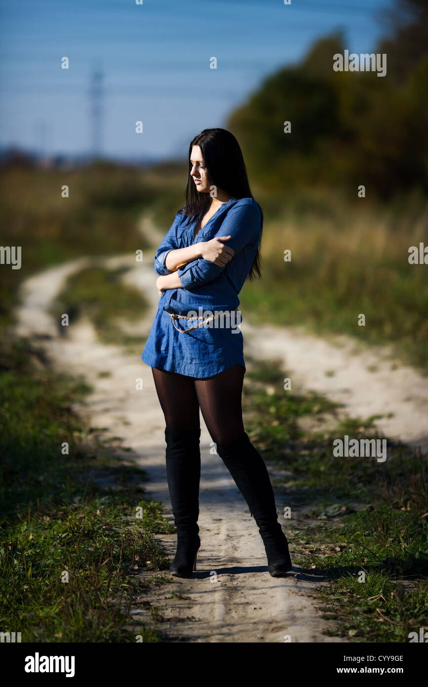 Sad young woman standing alone on country road Stock Photo - Alamy