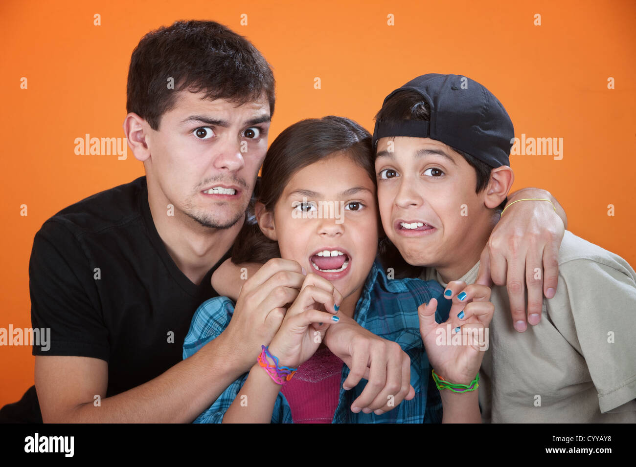 Elder brother with two younger siblings wearing a scared look Stock ...