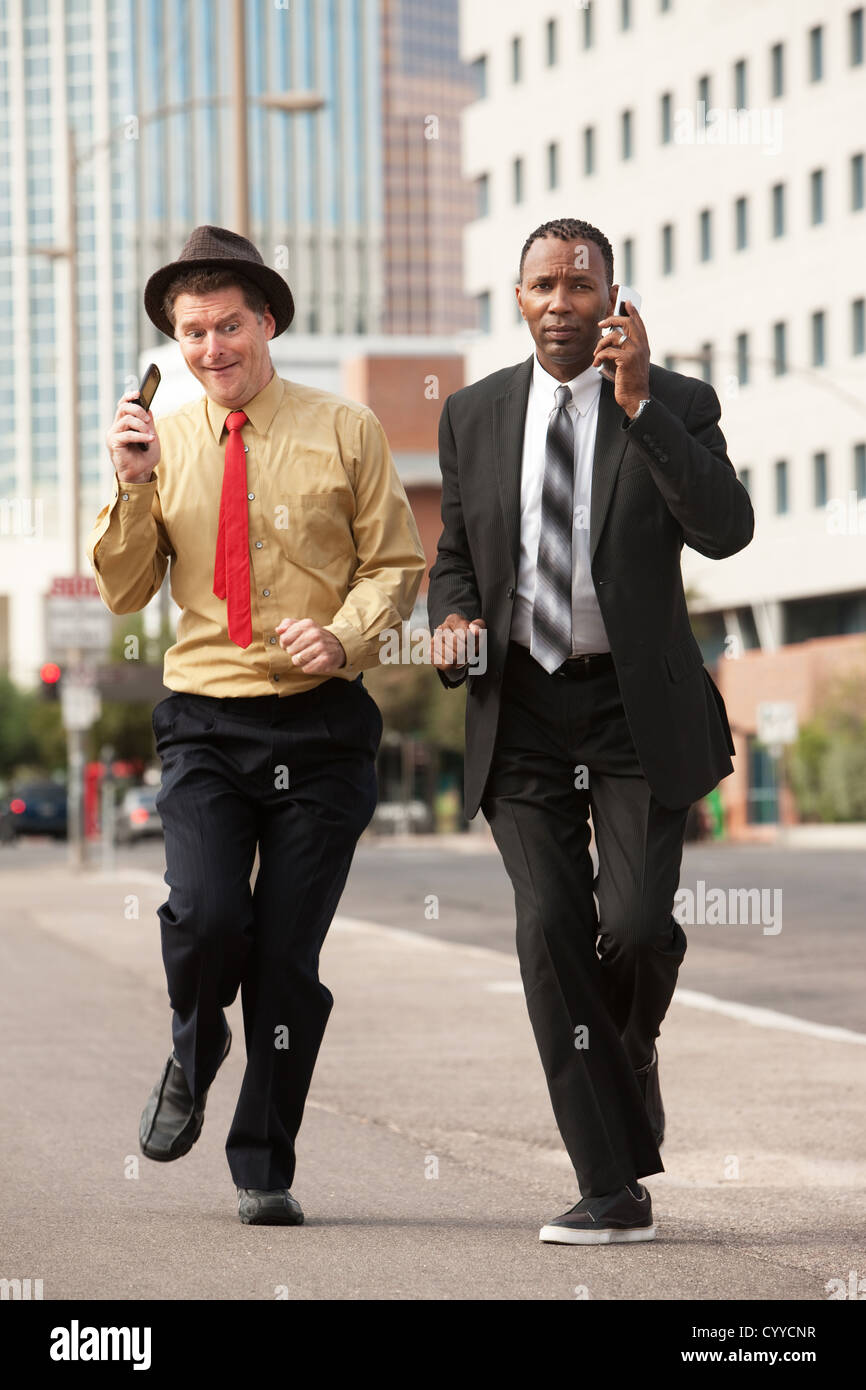 Two businessmen on phones rush down the street Stock Photo - Alamy