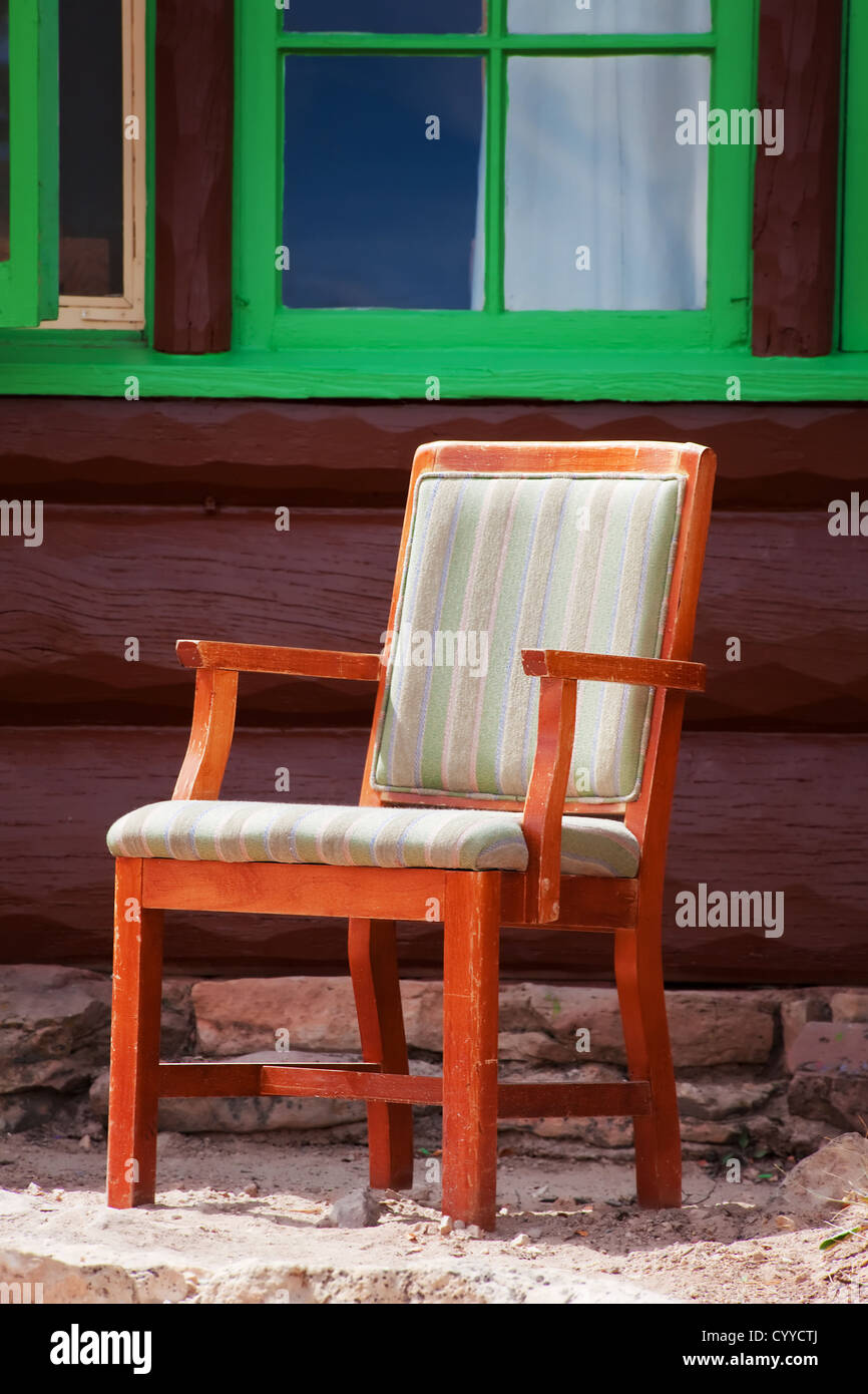 Rustic chair outside log cabin with green window Stock Photo - Alamy