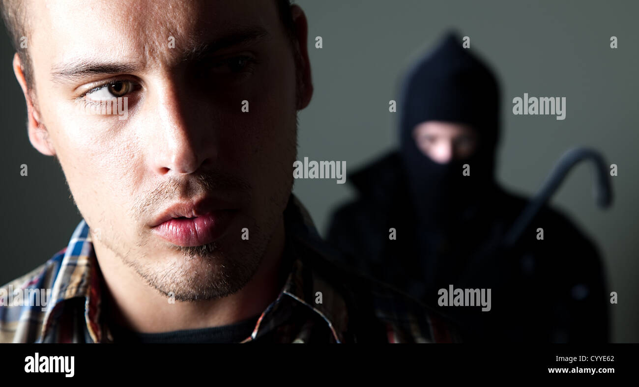 Man being stalked by criminal with crowbar Stock Photo - Alamy