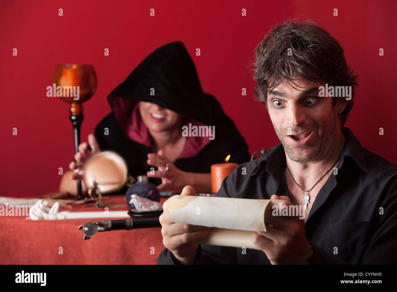 Man with scroll smiles with hooded fortuneteller in background Stock ...