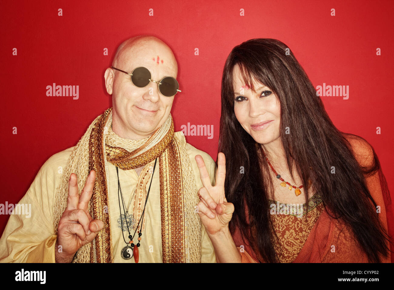 Smiling guru with woman gestures peace sign over maroon background ...