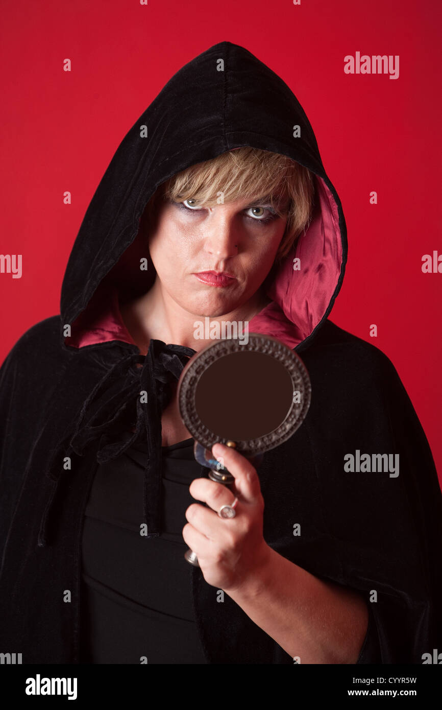 Witch in hood with scry mirror over red background Stock Photo - Alamy