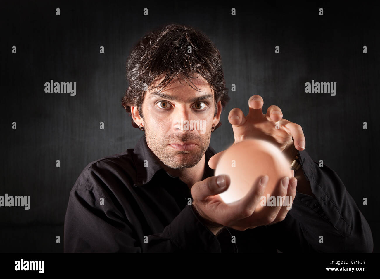 Serious fortune teller holds crystal ball over maroon background Stock ...