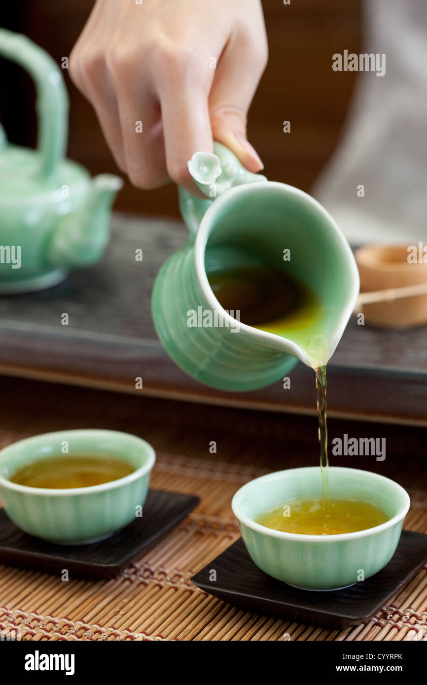Female hand pouring tea into tea cups Stock Photo - Alamy
