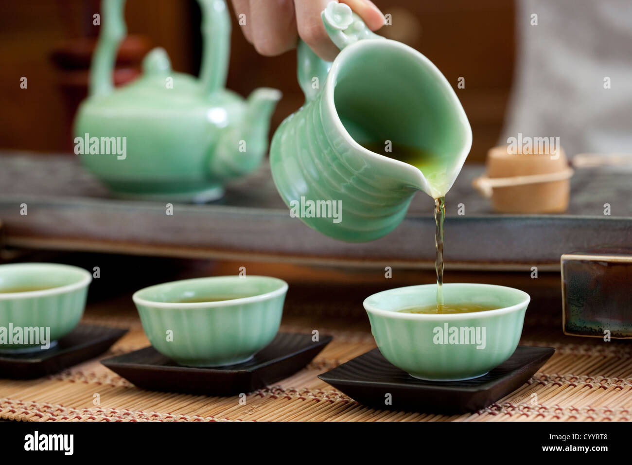 Female hand pouring tea into tea cups Stock Photo - Alamy