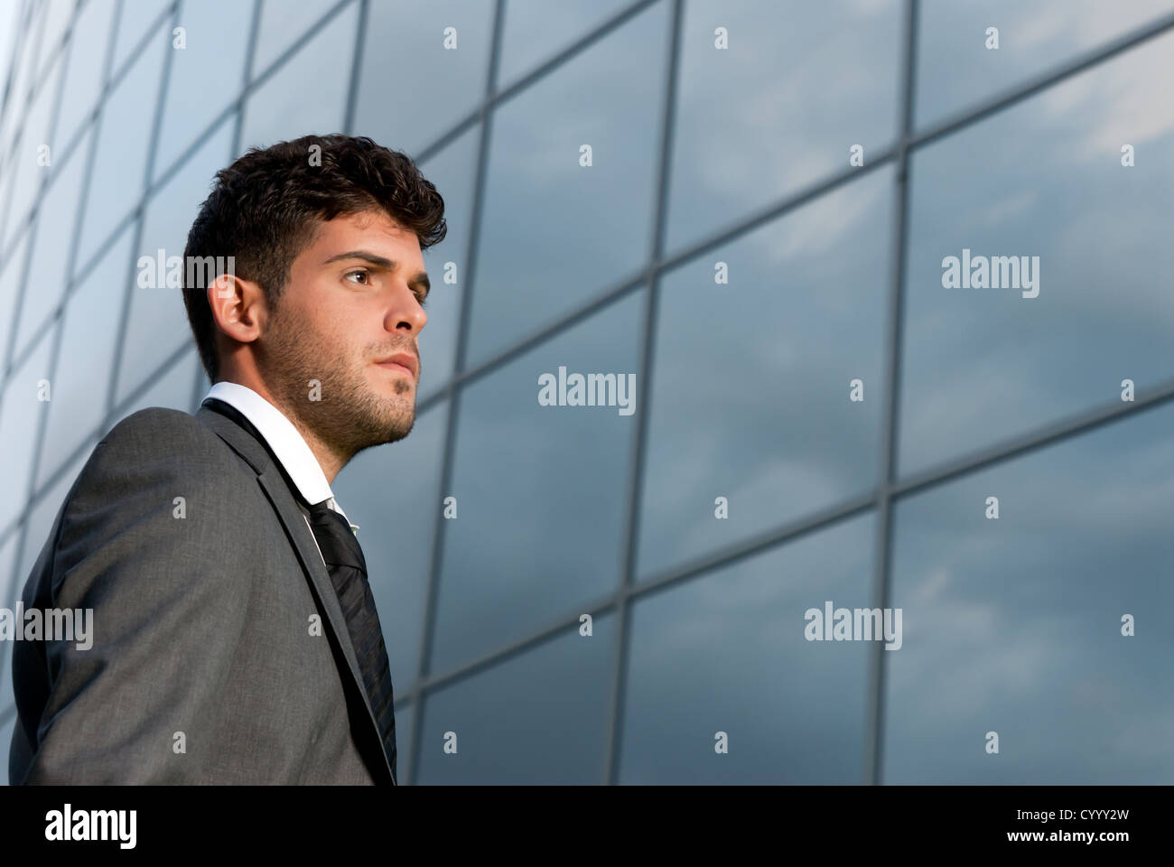 Young businessman looking to good future on modern building background ...