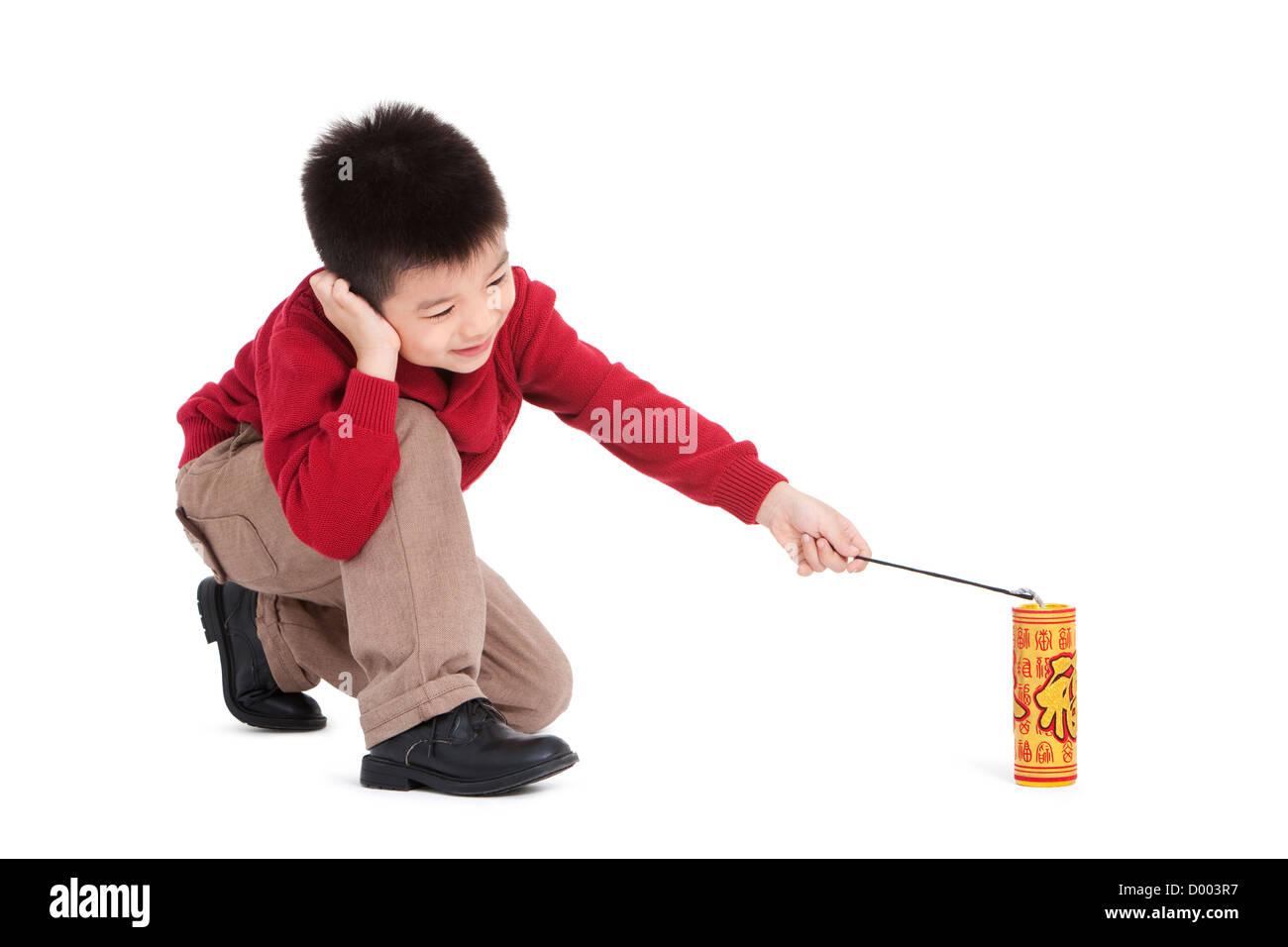 Little boy igniting firecracker with hands covering ears Stock Photo ...