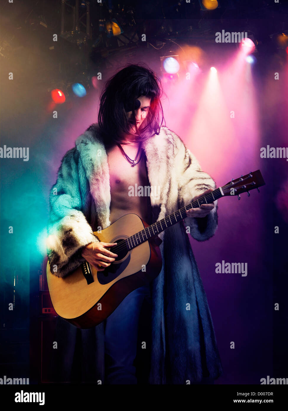 Young rock musician in fur coat playing guitar at concert Stock Photo ...