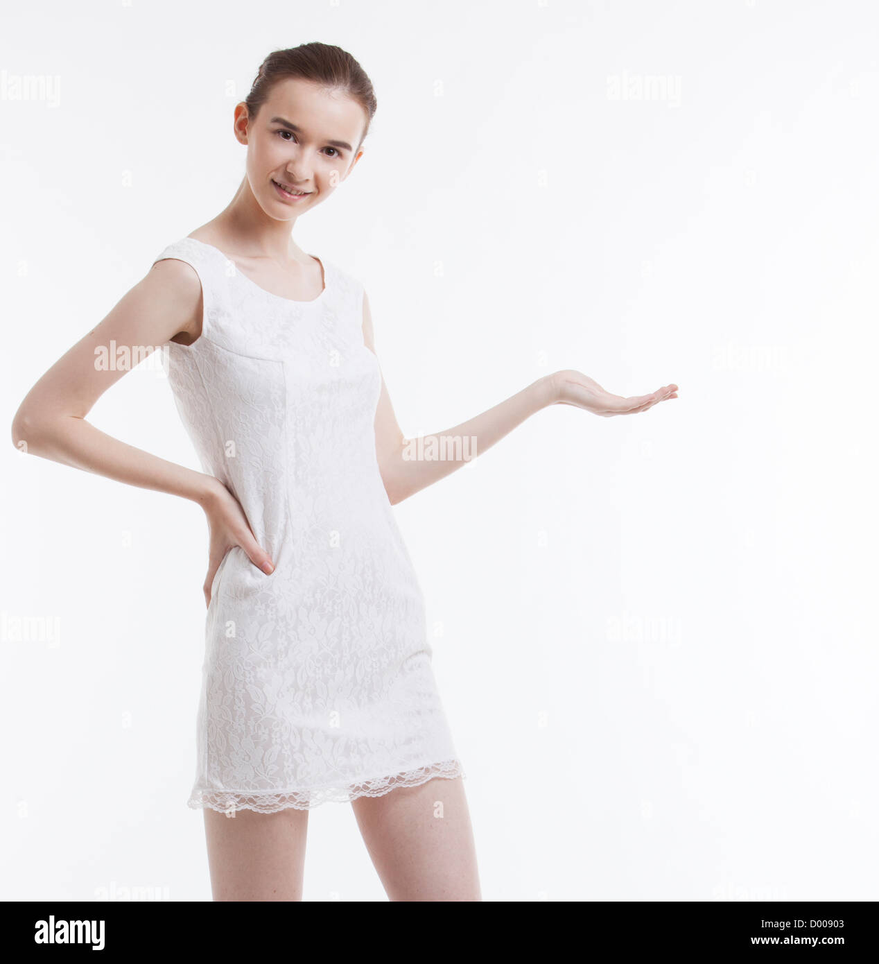Portrait of young woman in dress with hand on hip over white background ...