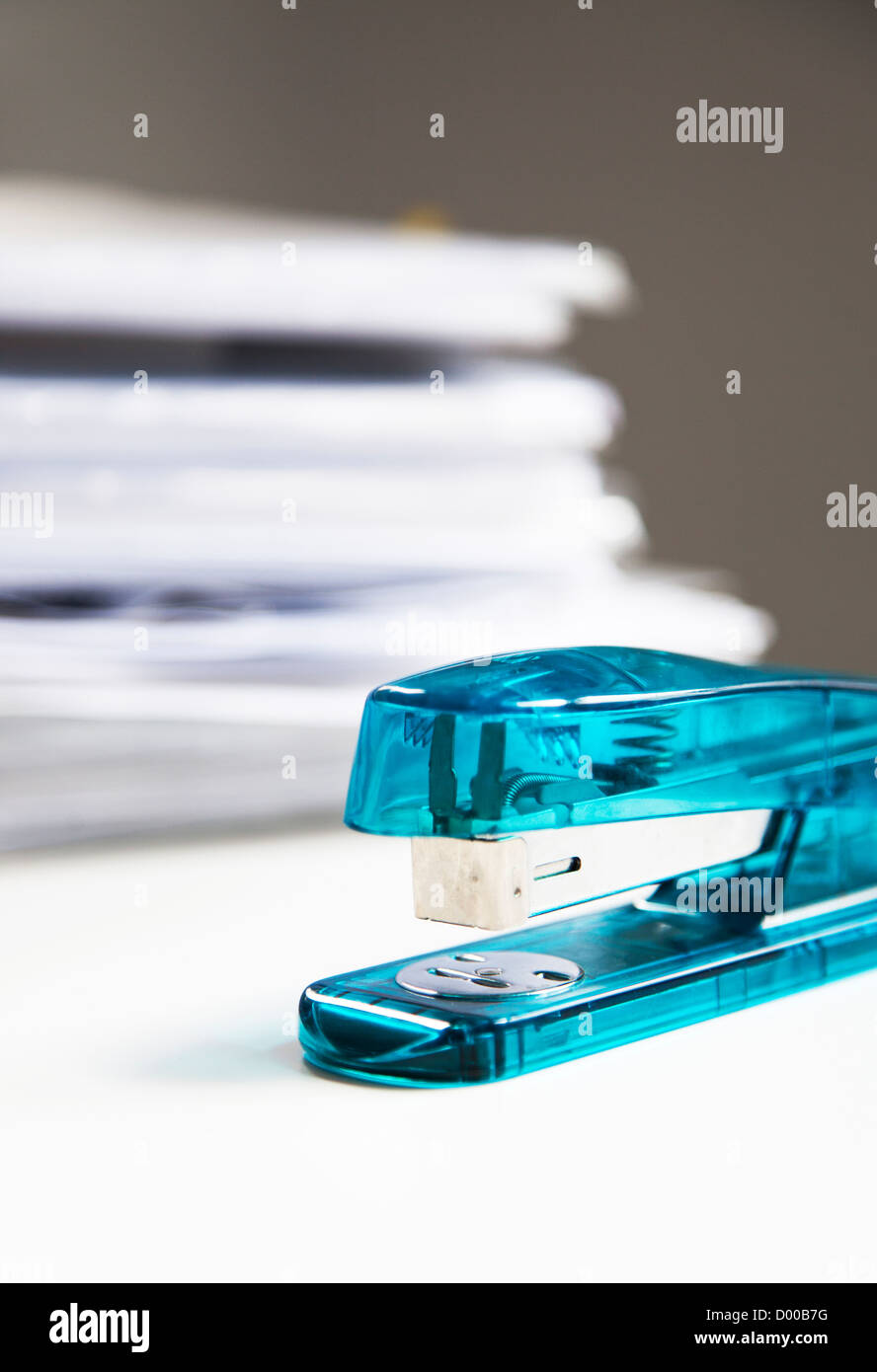 Stapler on white table with stack of papers in background Stock Photo ...