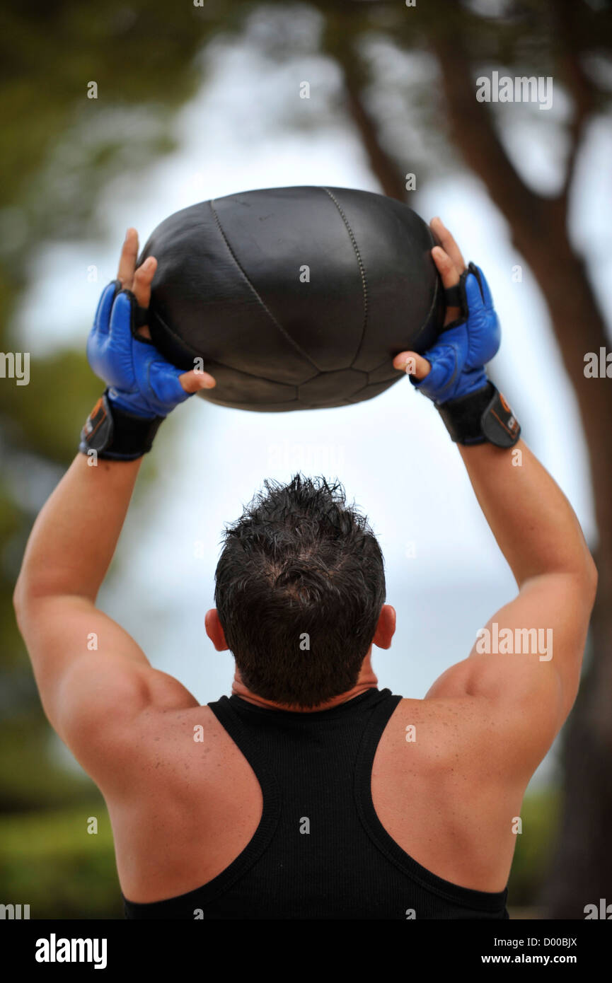 man in his thirties lifts medicine ball in park Stock Photo - Alamy
