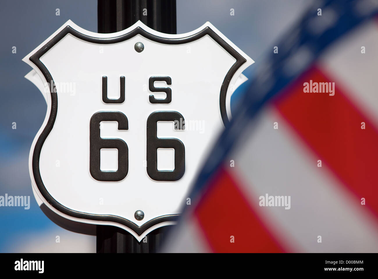 Route 66 sign on side of road with American flag Stock Photo - Alamy
