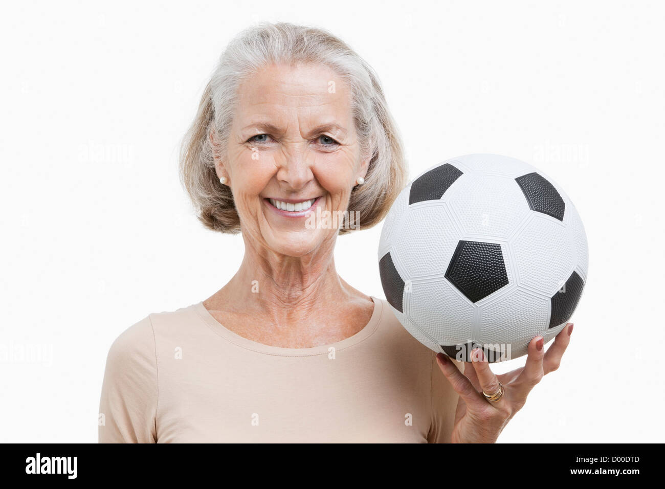 Portrait of senior woman holding soccer ball against white background ...
