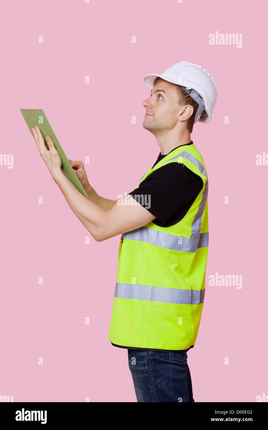 Side view of a male construction worker with clipboard looking away ...