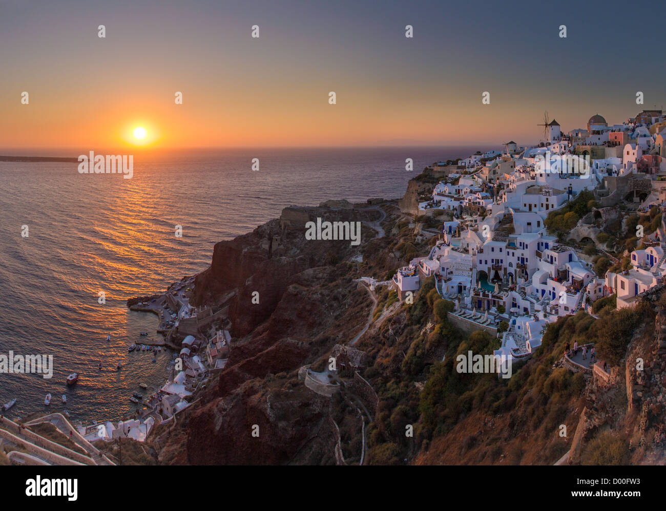 Traditional houses, harbour and windmill in Oìa at sunset Stock Photo ...