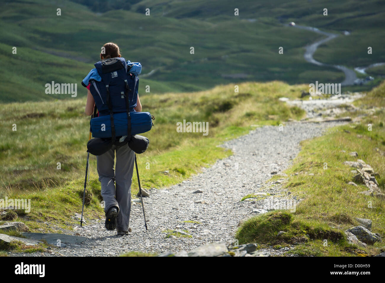 A woman hiker walking along a long stone path with a large backpack in ...