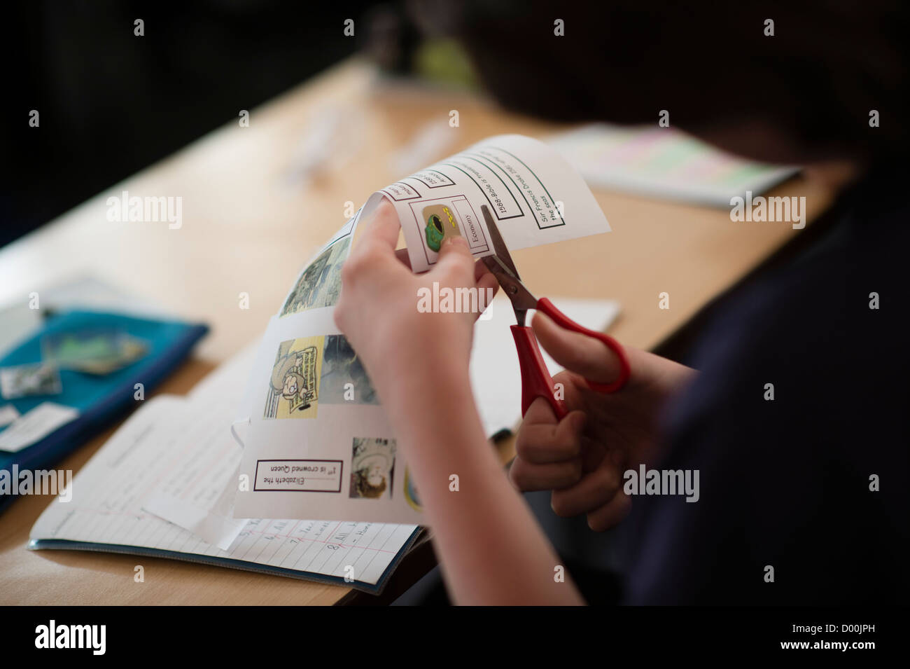 A pupil cutting up labels in class at a secondary comprehensive school ...