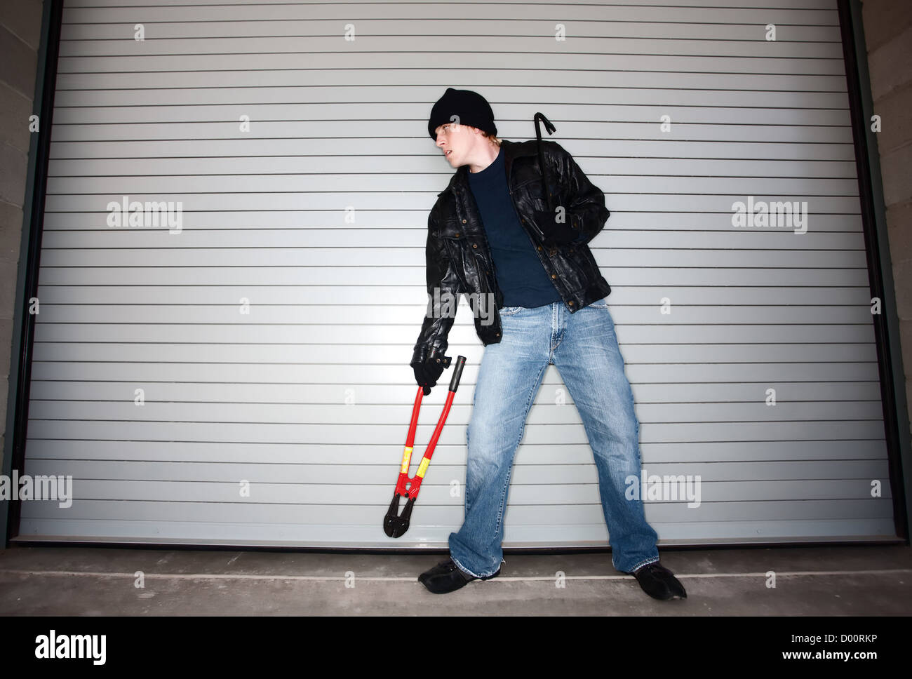 Burglar with tools in front of industrial door Stock Photo - Alamy
