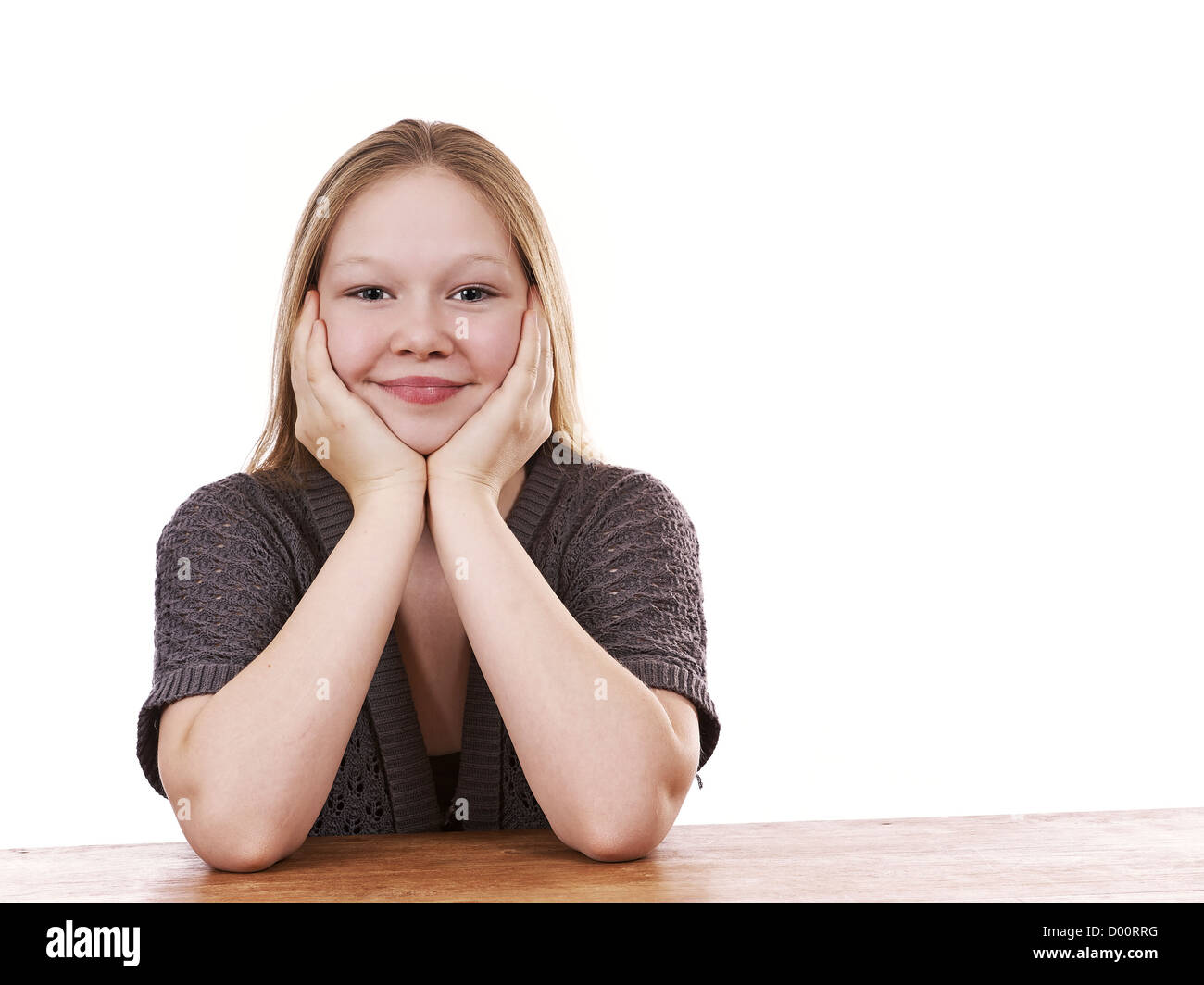 Beautiful happy young girl sitting by table on white background Stock ...