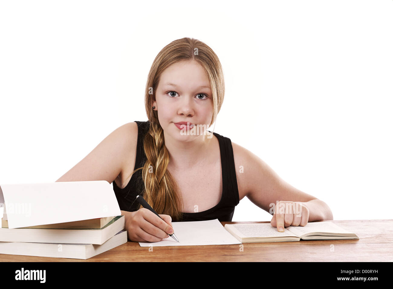 Beautiful young girl sitting by table and writing on white background ...