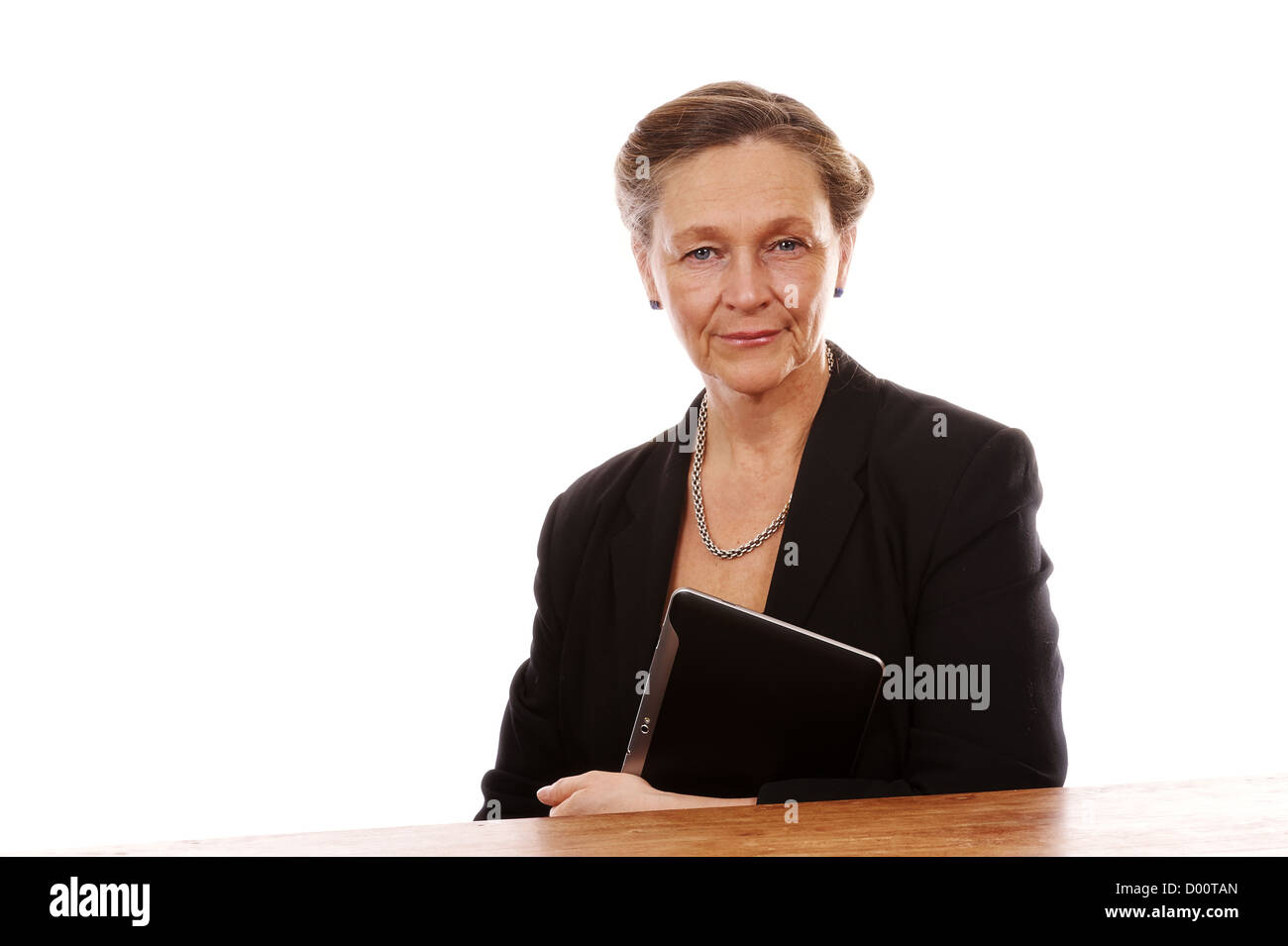 Mature woman sitting by table holding tablet computer on white ...