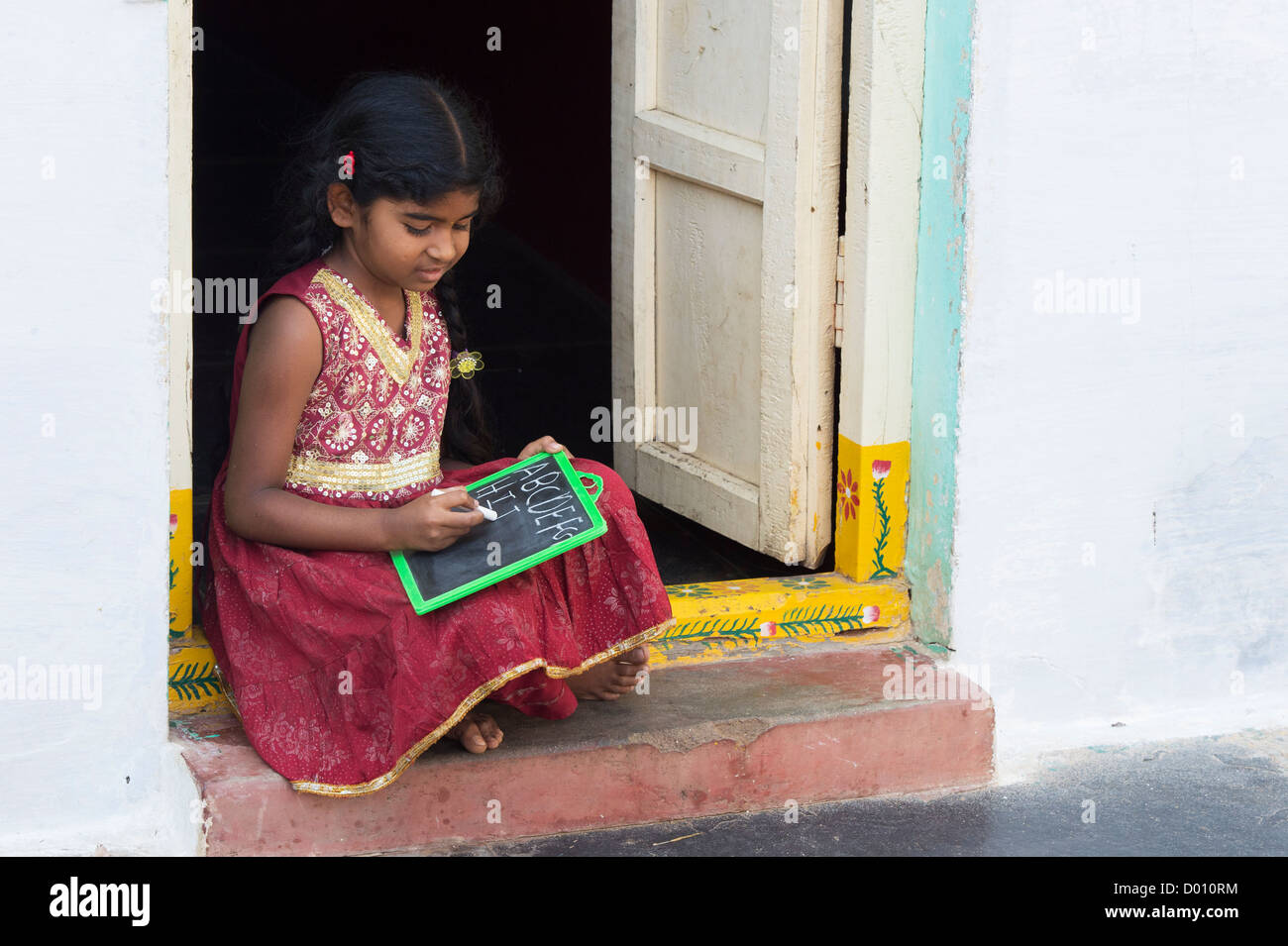 Indian village girl writing english alphabet on a chalkboard in a rural ...