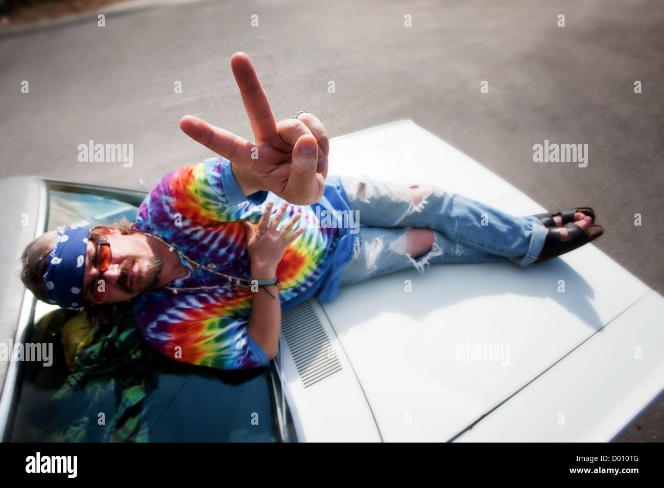 Hippie on the hood of car making peace sign Stock Photo - Alamy