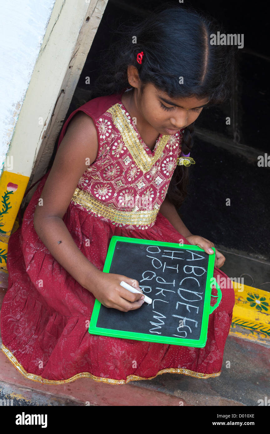 Indian village girl writing english alphabet on a chalkboard in a rural ...