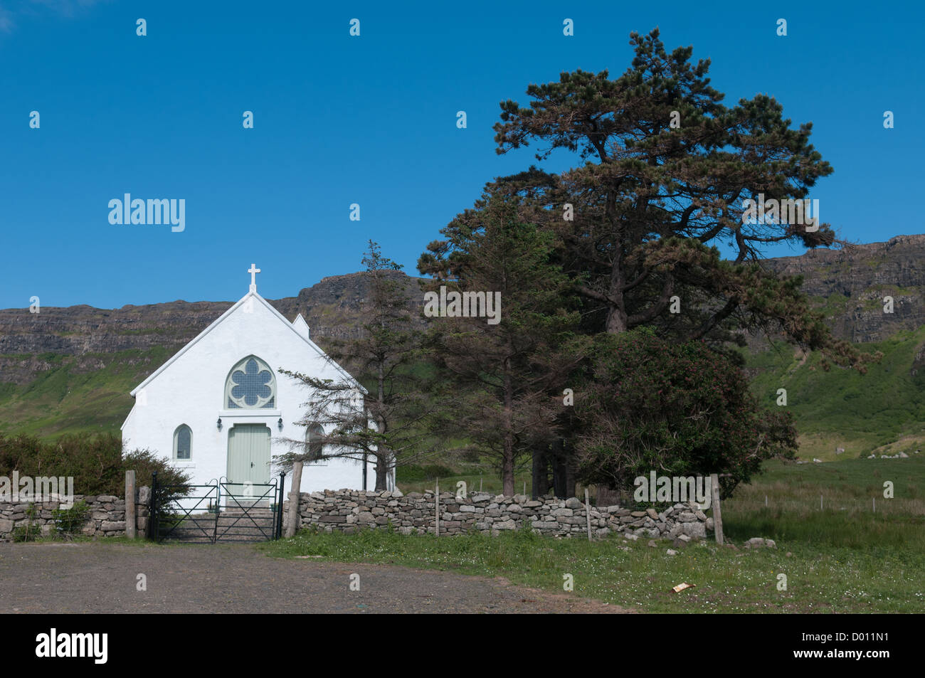 White church with blue sky and green trees on the Island of Eigg ...