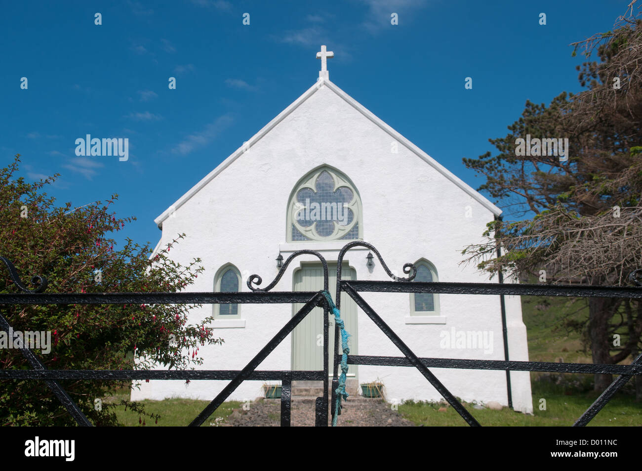 White church with blue sky and green trees on the Island of Eigg ...
